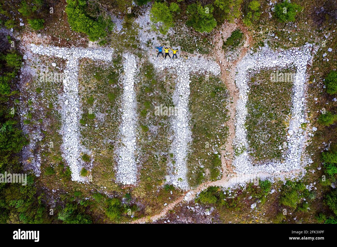 Aerial shot of Tito inscription from stones and a family laying on the ...