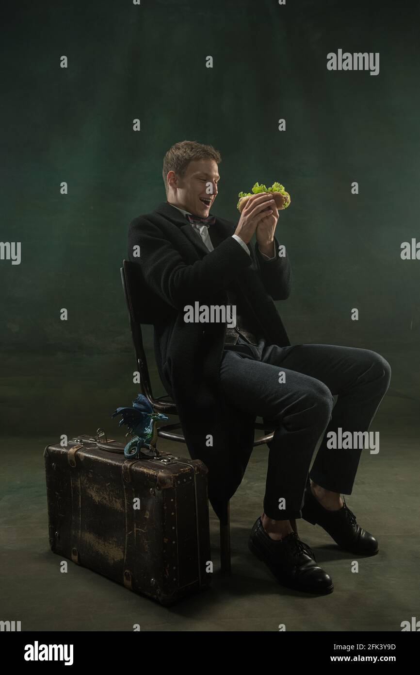 Young man in art action isolated on dark green background. Retro style ...