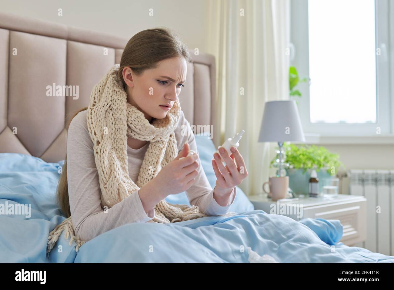 Young sick woman sitting in bed with nose drops and handkerchief Stock ...