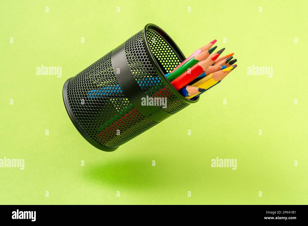 Colored pencils in a black mesh pen pot on a green background Stock ...
