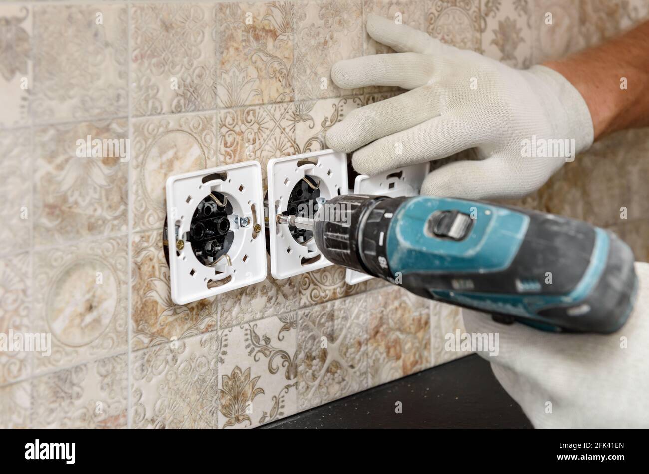 An electrician is installing switches and sockets on the wall Stock ...