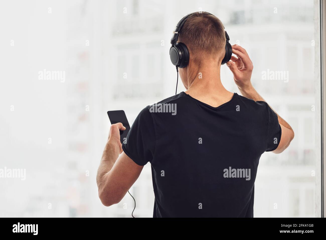 The man in headphones and with a smartphone. Back view Stock Photo - Alamy