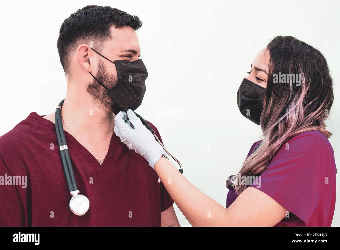 Closeup of two medical nurses in facemasks flirting with each other ...