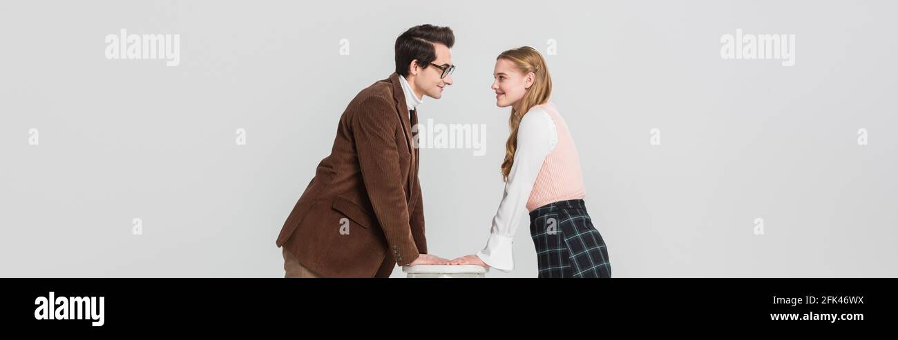 side view of retro style couple looking at each other isolated on grey ...