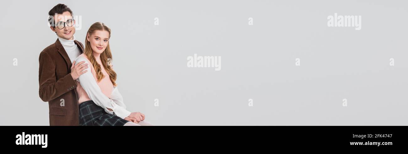 smiling man embracing pretty woman in plaid skirt sitting isolated on ...