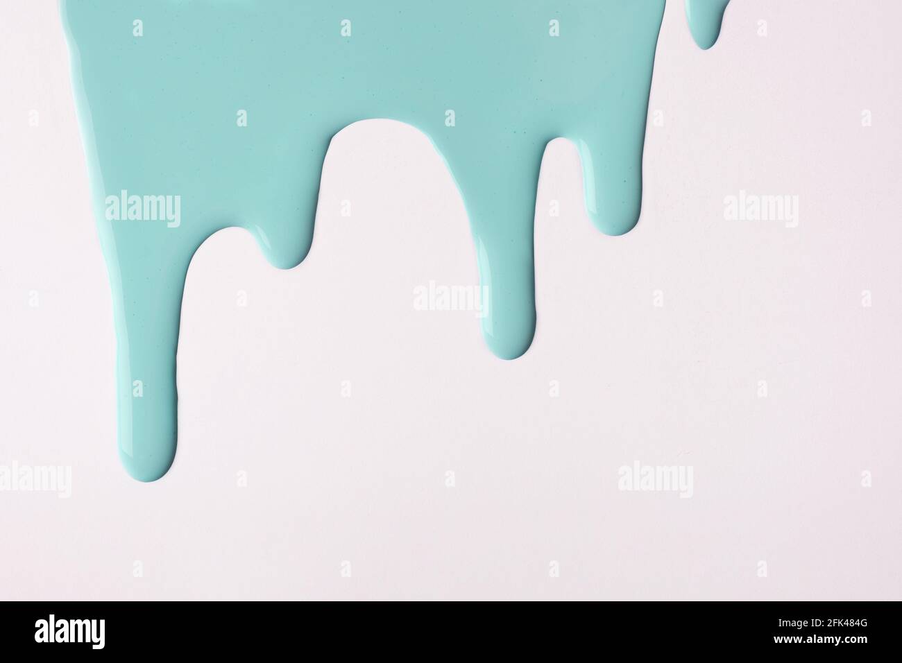 Light cyan liquid drops of paint color flow down on isolated white ...
