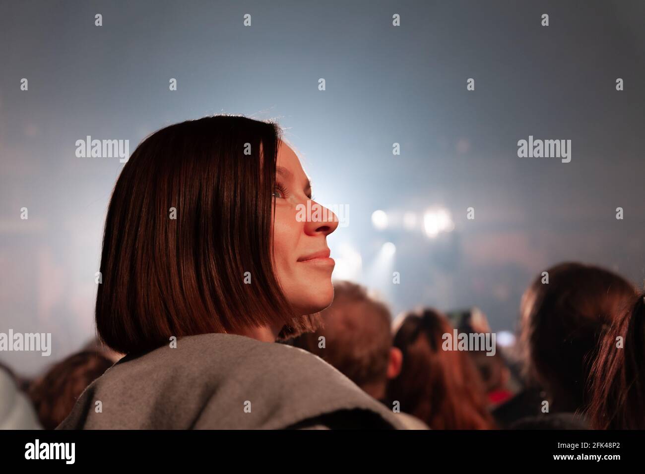 Girl standing at concert on background of people crowd and neon light ...