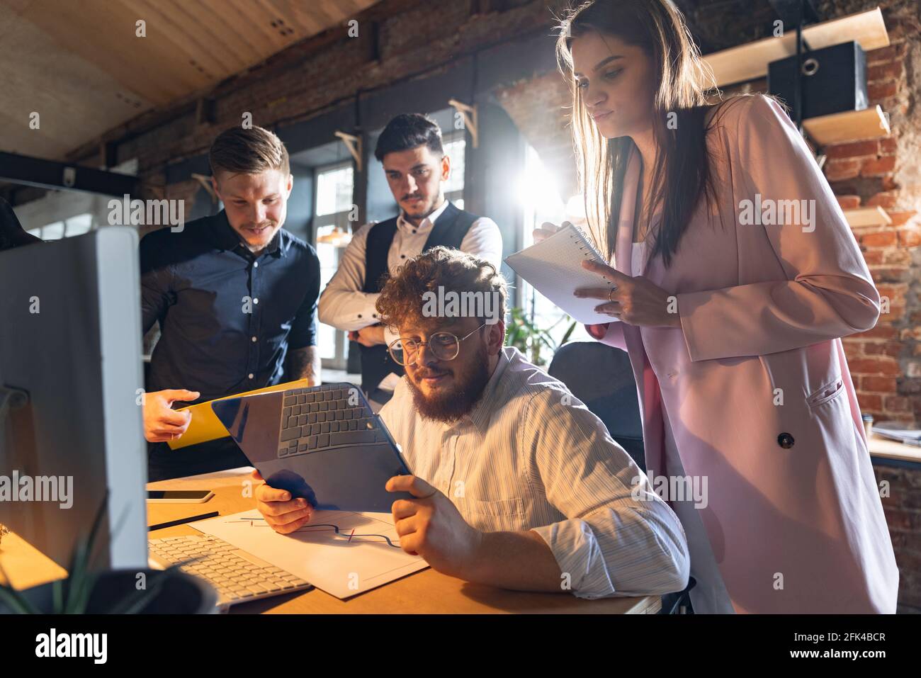 Colleagues working together in modern office using devices and gadgets ...