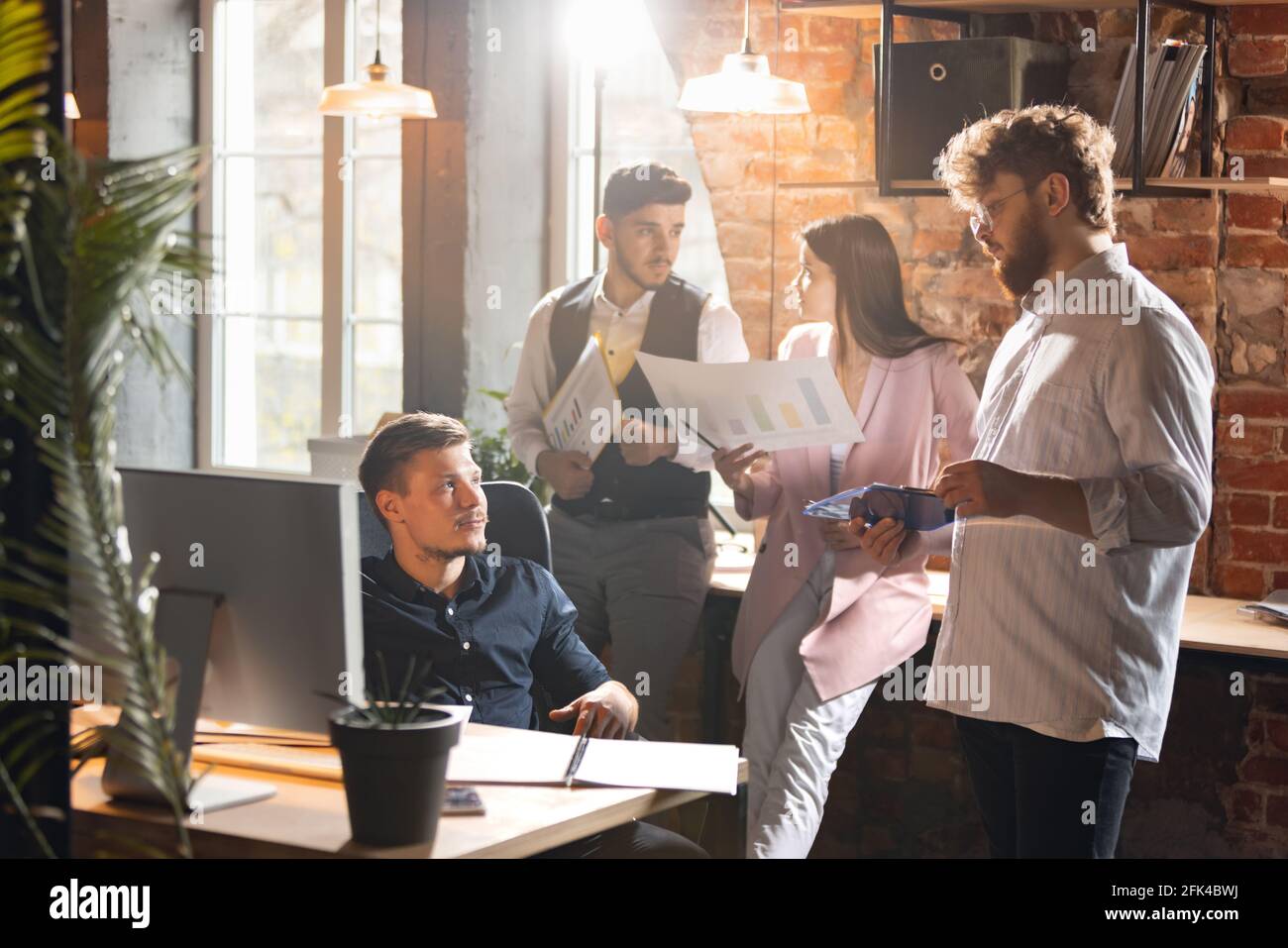 Colleagues working together in modern office using devices and gadgets ...