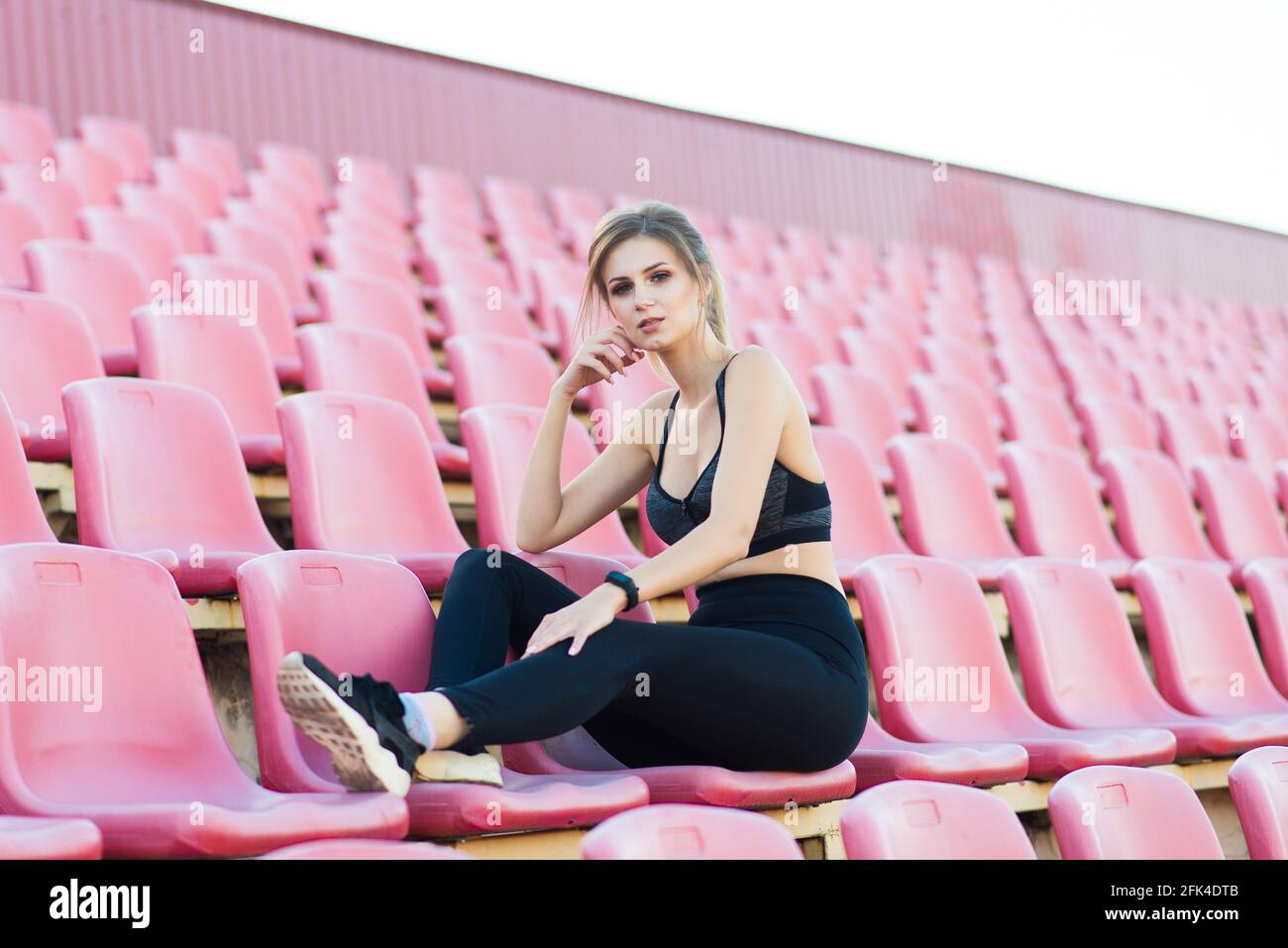 A female coach with dark hair stands on the red running track of the ...