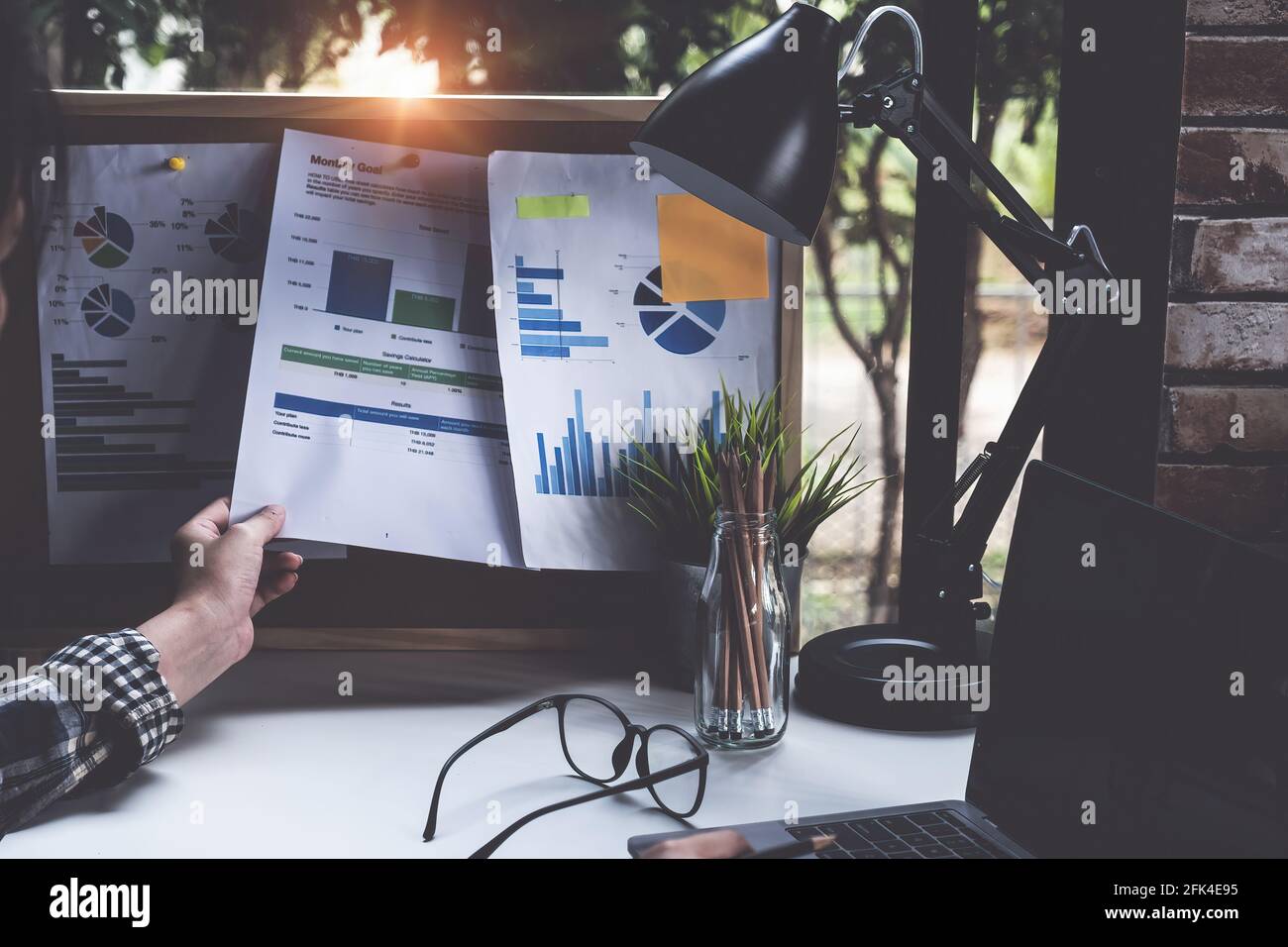 Project management updating financial chart with paperwork on board ...