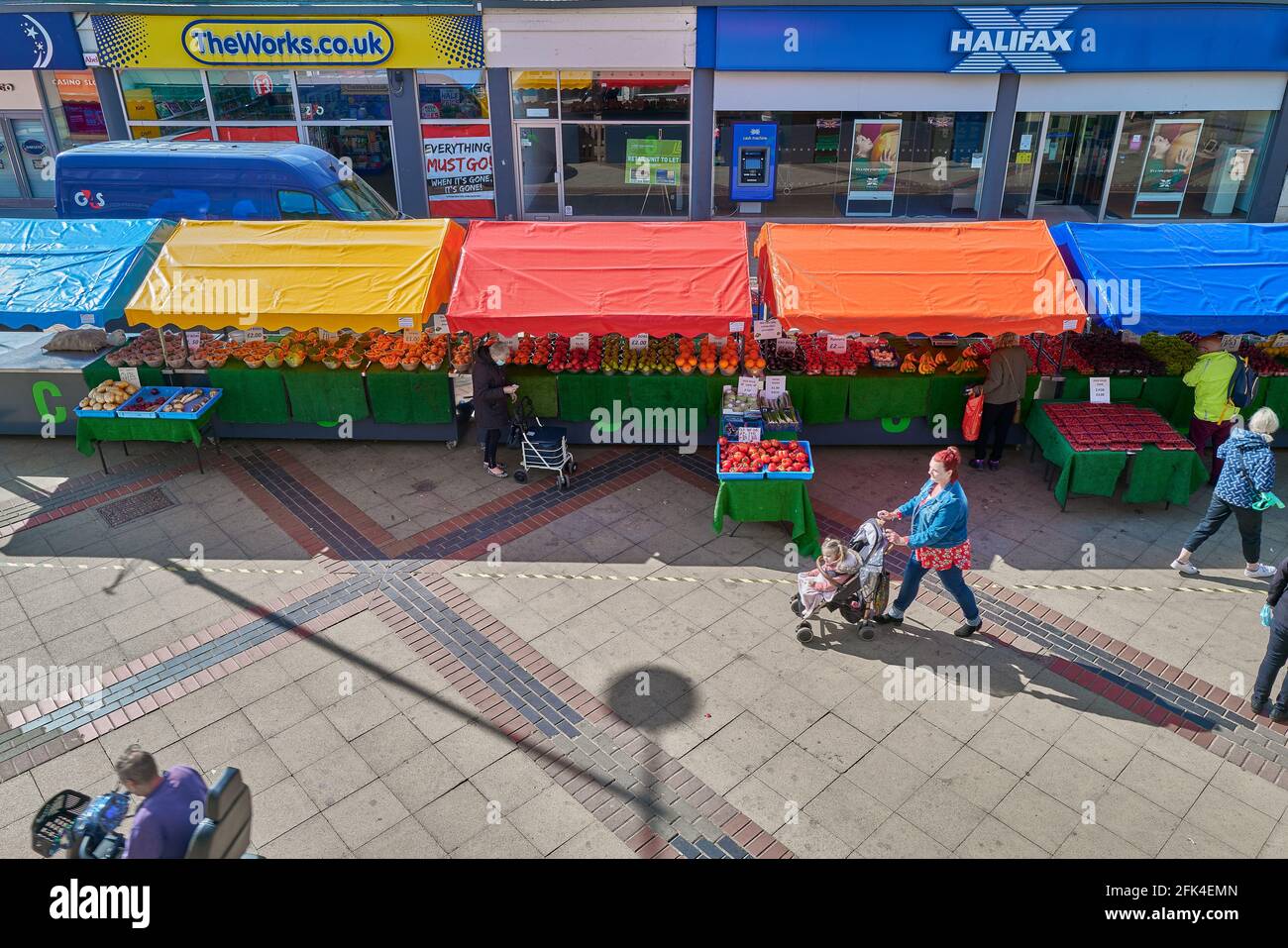 Shoppers pass grocery market stalls at Corby town shopping centre ...