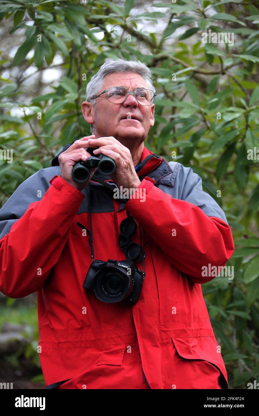 Male Bird watcher and photographer in local park using camera and ...