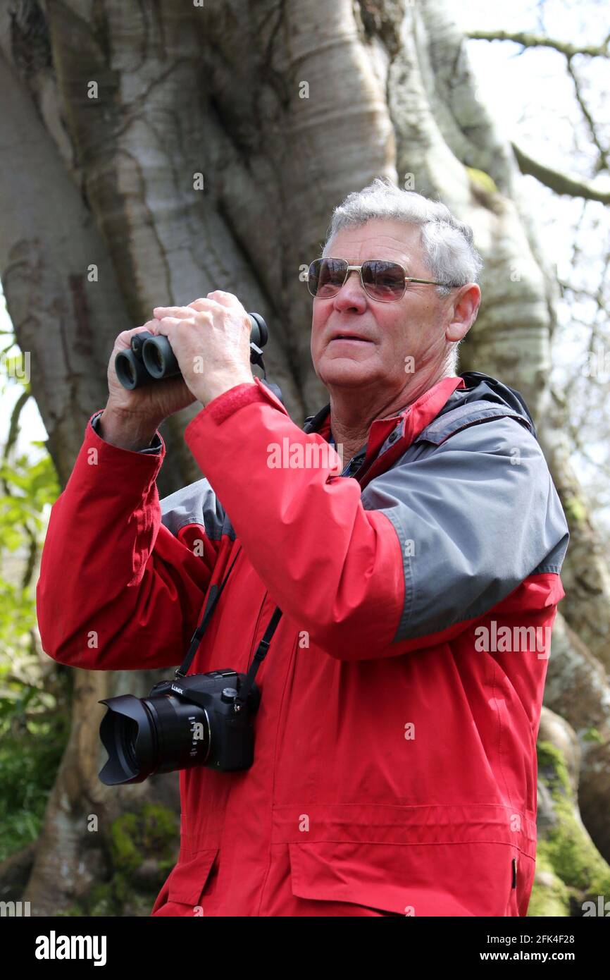 Male Bird watcher and photographer in local park using camera and ...