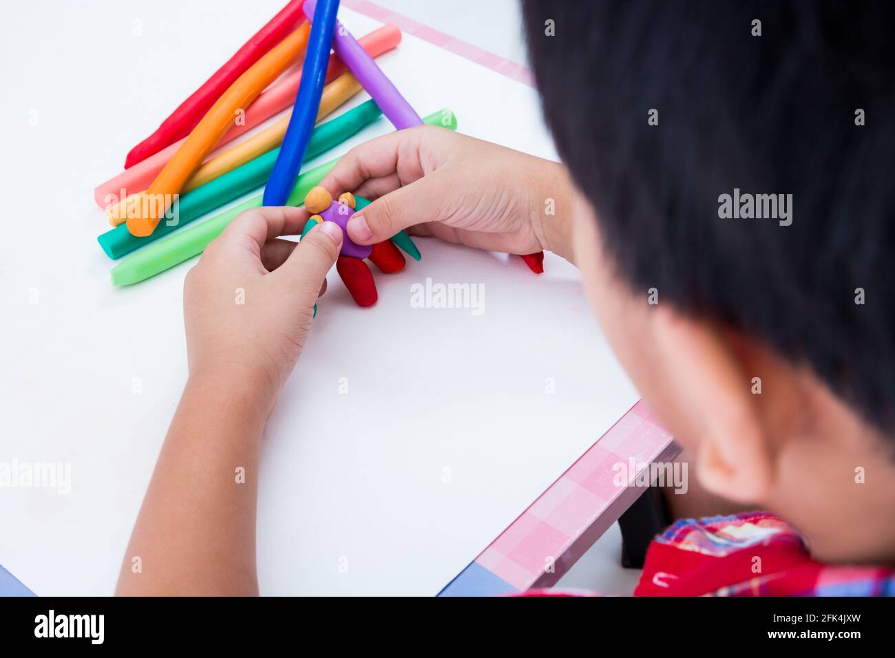 Little boy playing and creating toys from play dough. Child moulding ...
