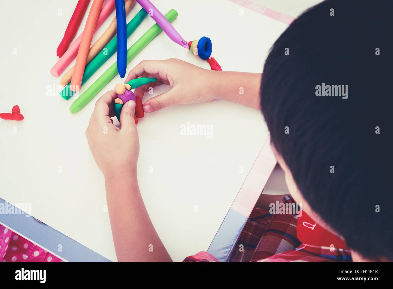 Little boy playing and creating toys from play dough, on white ...