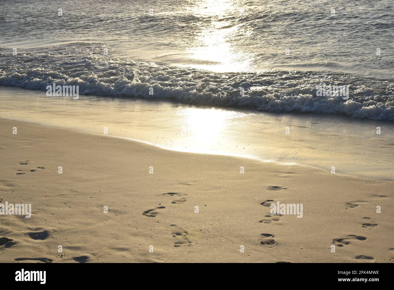 beach with footprints and wave's in de background with sunset ...