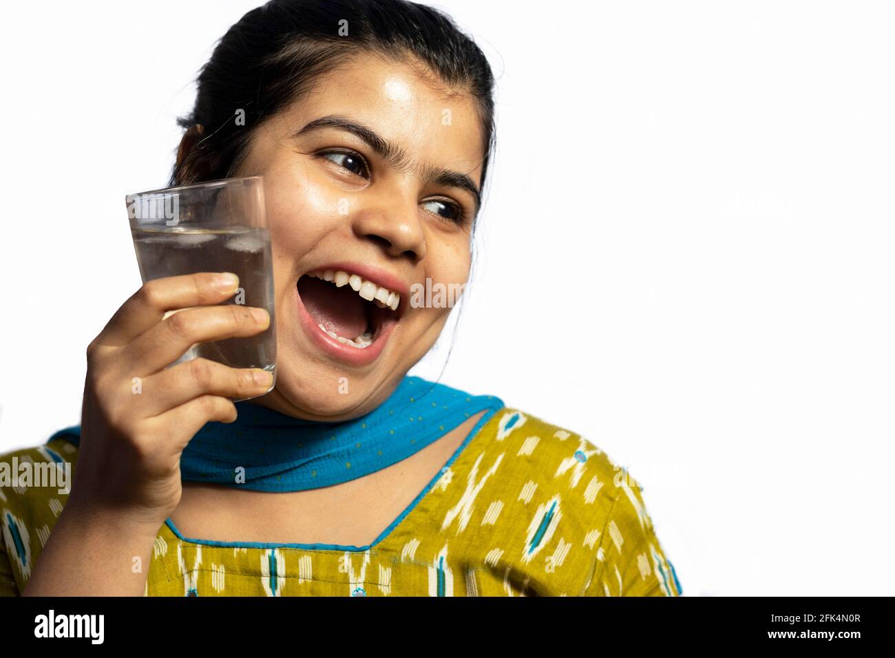 An Indian Asian woman with a glass of cold water touching on her cheek ...