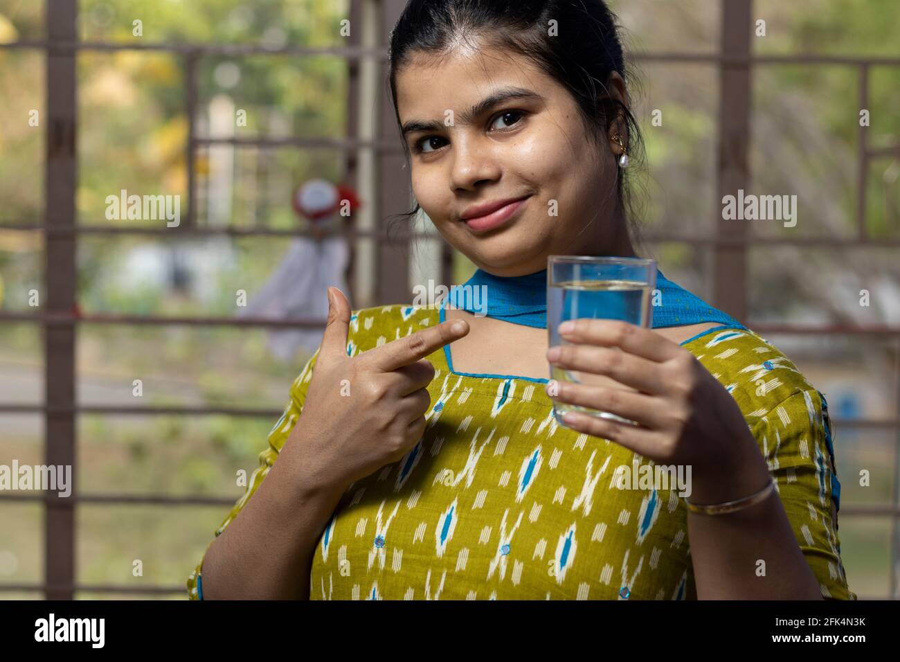 An Indian Asian woman pointing towards a glass of water with smiling ...