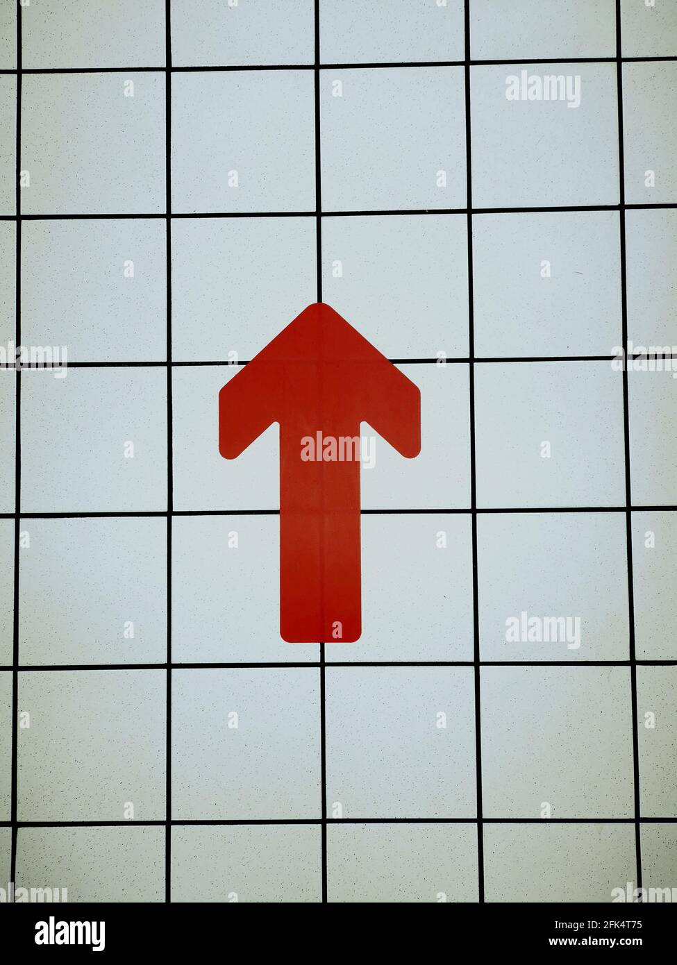 Shot of a red arrow on a white tile floor Stock Photo - Alamy