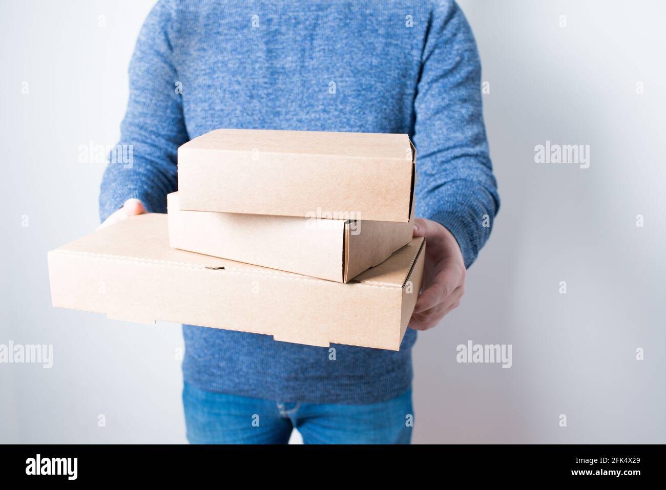 Young anonymous adult delivering three cardboard boxes, with white ...