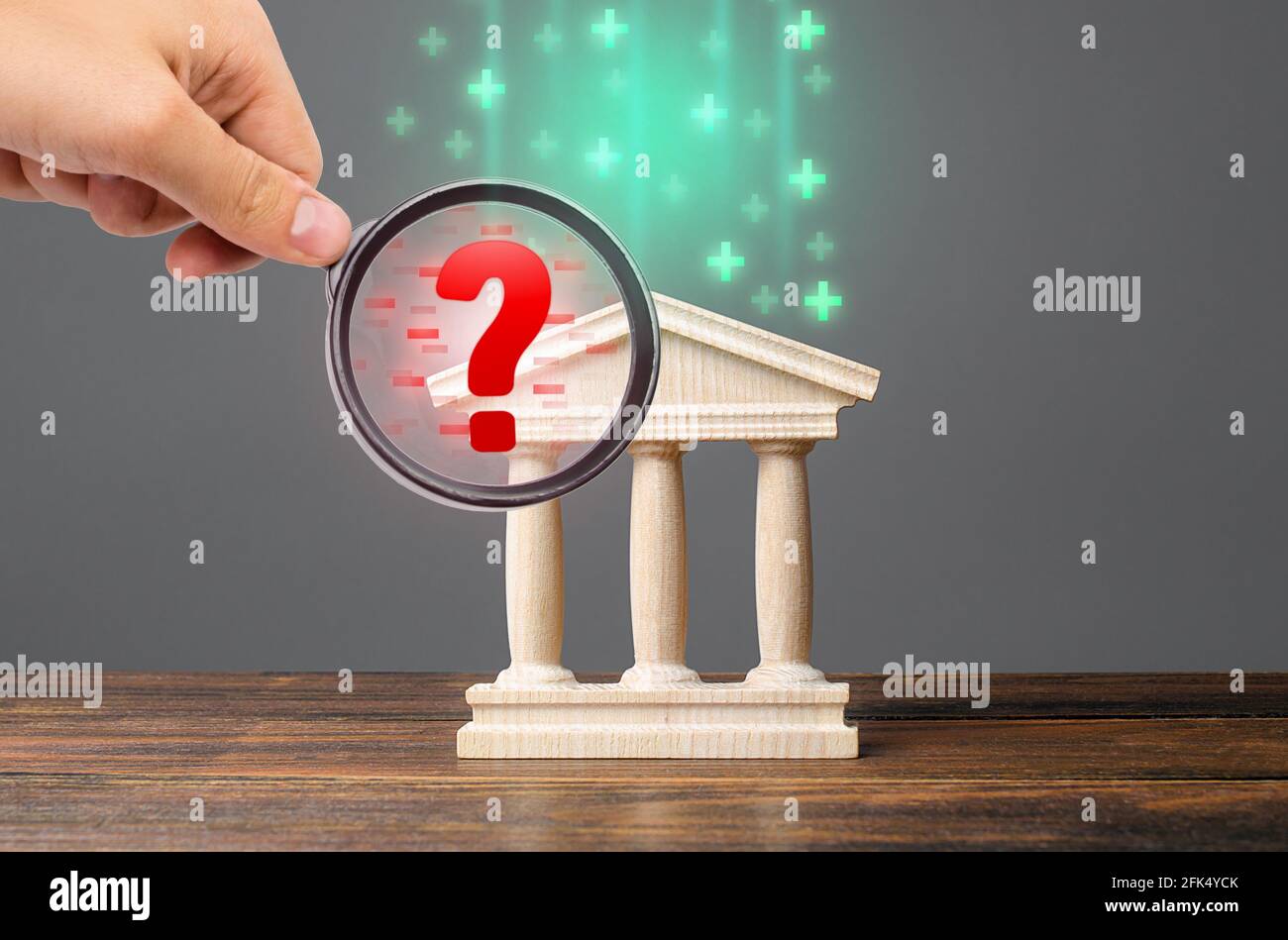 A hand with a magnifying glass inspects bank and finds financial ...