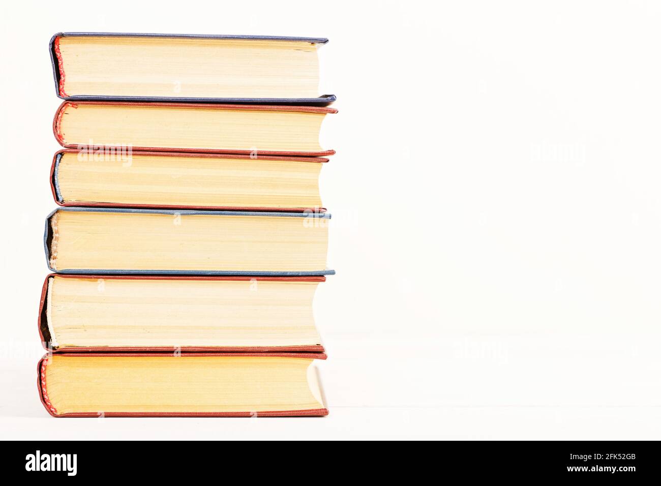 A stack of old books on a light beige background. Copyspace. Front view ...