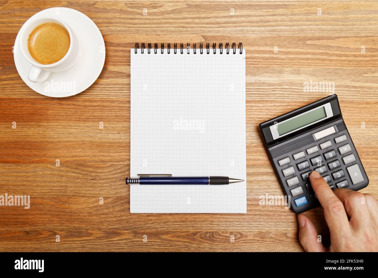 Wooden desktop with blank notebook and pen in the center. Near cup of ...