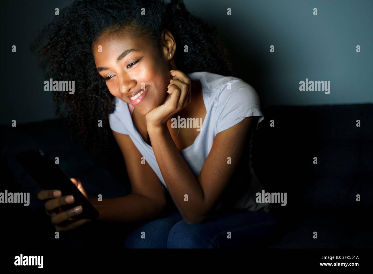 Woman uses smartphone at night. Face is Illuminated with a screen light ...