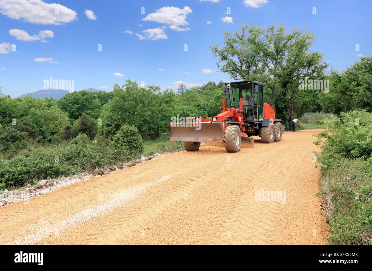 Grader spreading gravel with white background Stock Photo - Alamy