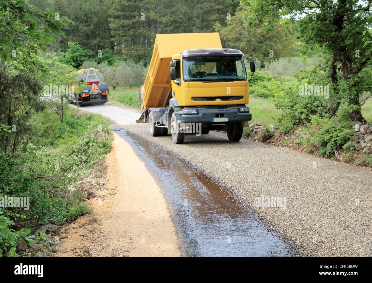 Construction of a road by trucks with aggregates and tar Stock Photo ...