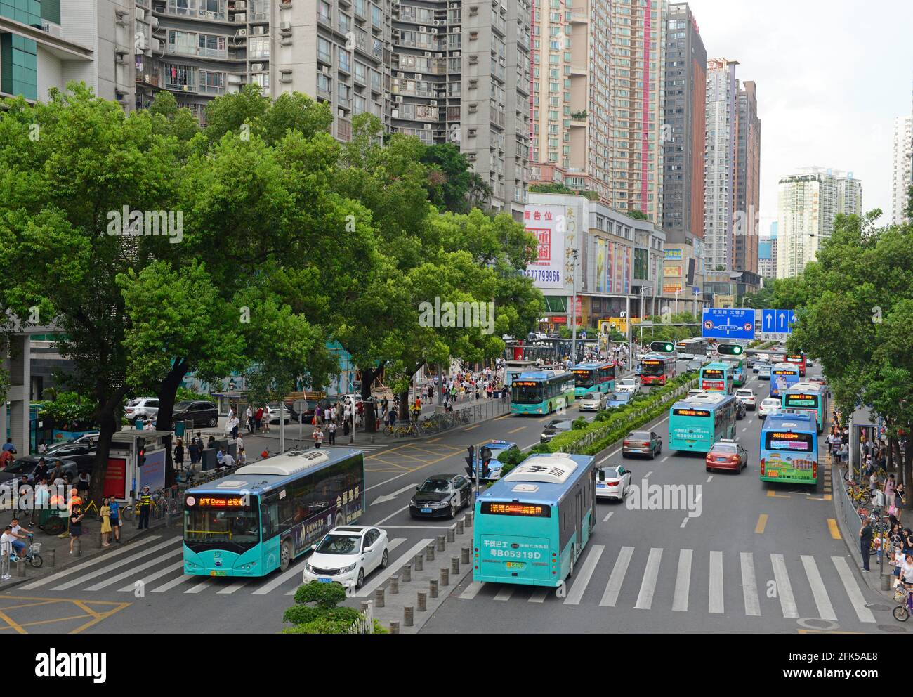 A shopping street in Shenzhen, China with many buses passing, lined by ...
