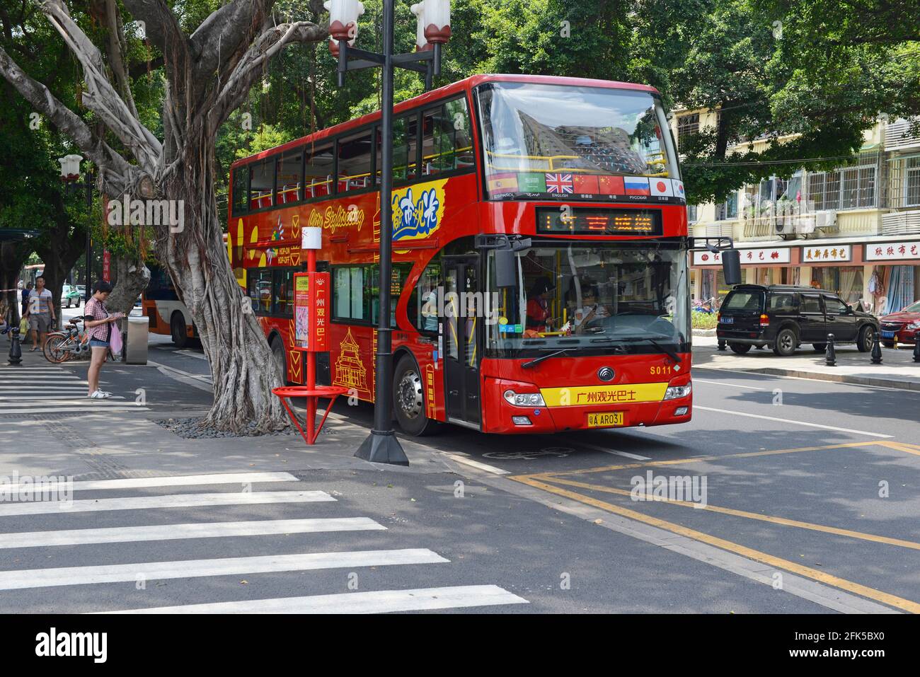 A double deck sightseeing bus stops at a bus stop in central Guangzhou ...