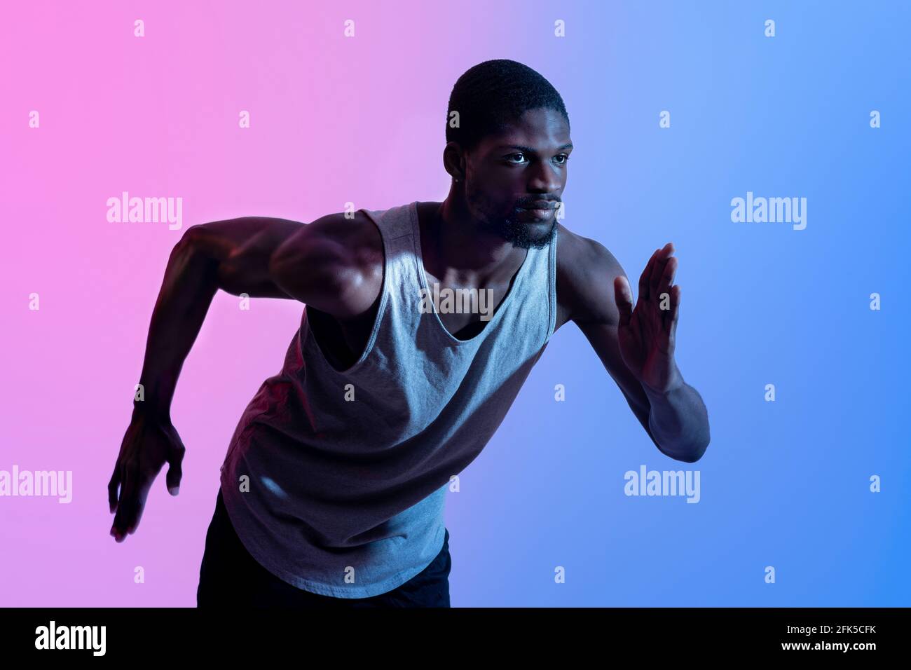 Portrait of young black sprinter running in neon light. Professional ...