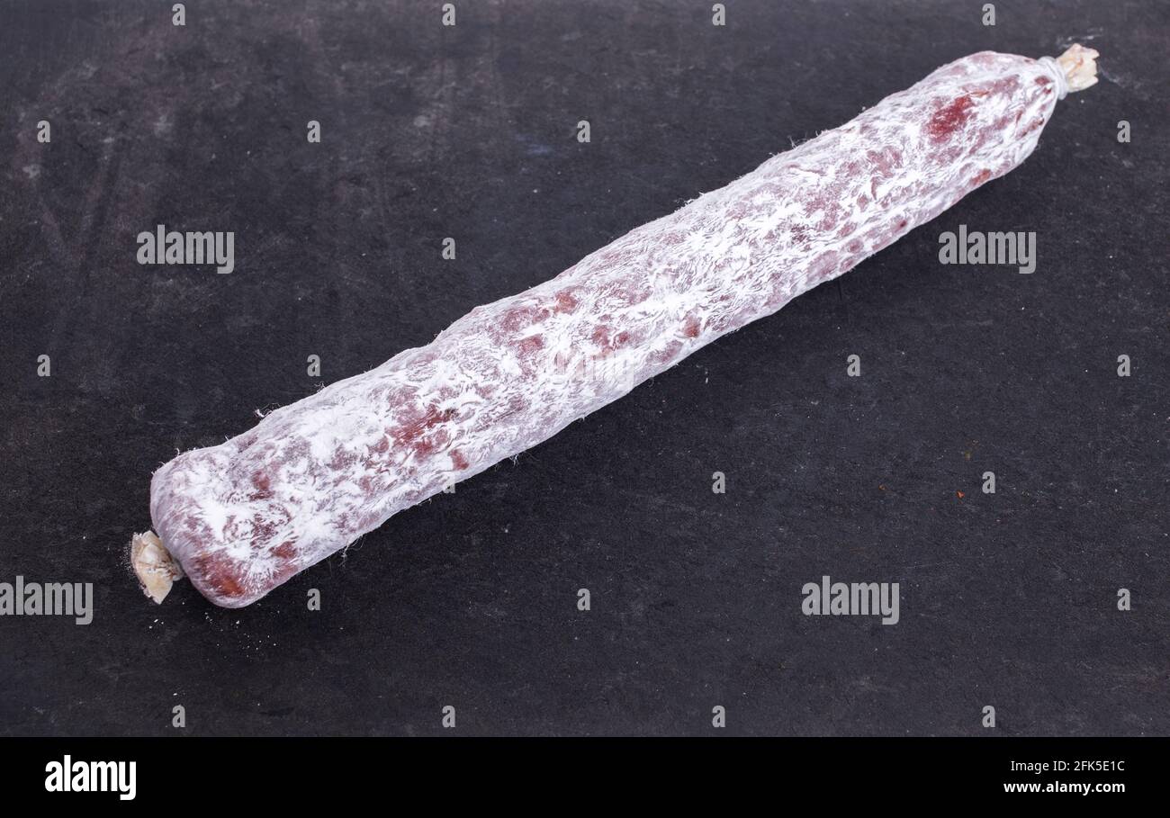 Delicious italian felino salami stick. Located on black cardboard ...