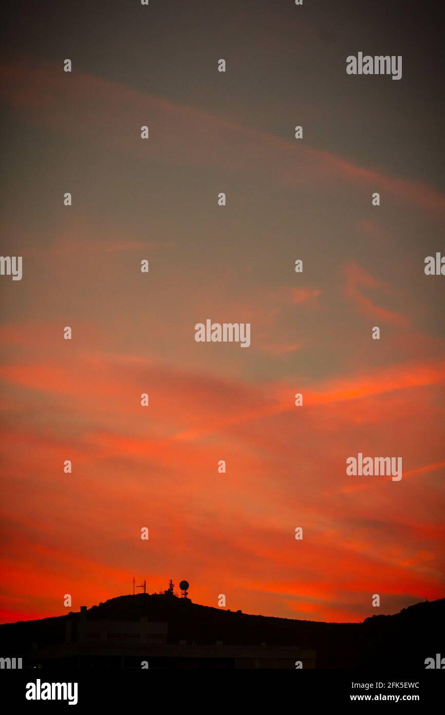 Vertical shot of fiery red sunset seen through a mountain silhouette ...