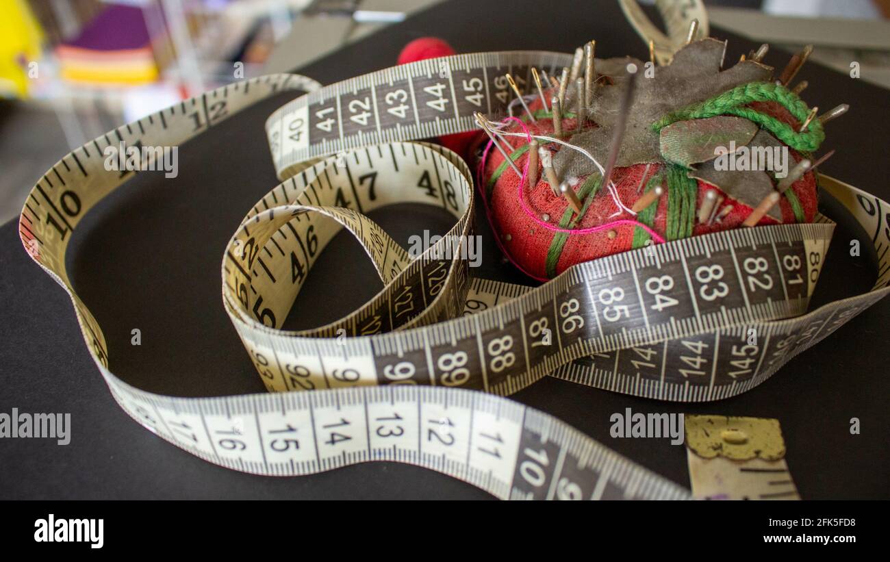 Measuring tape, spool of thread and needles on a black surface Stock ...
