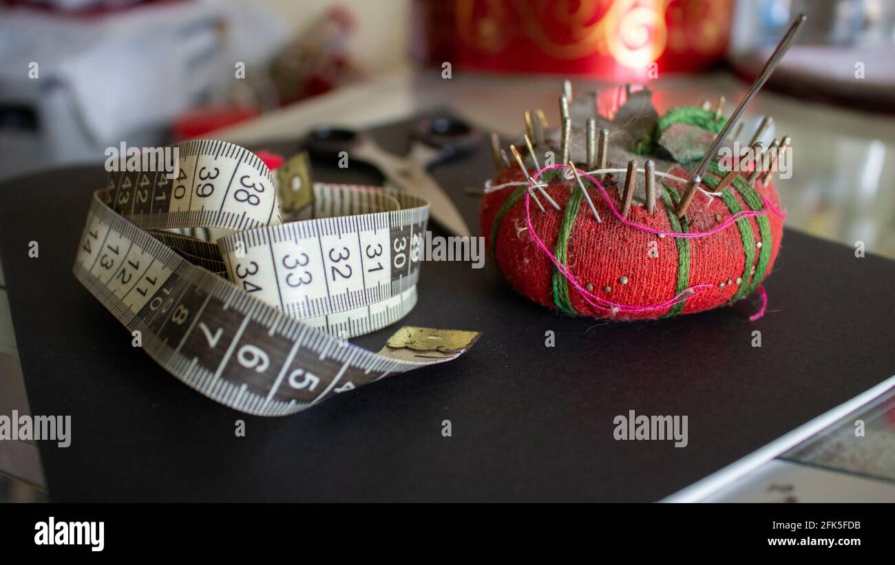 Measuring tape, spool of thread and needles on a black surface Stock ...