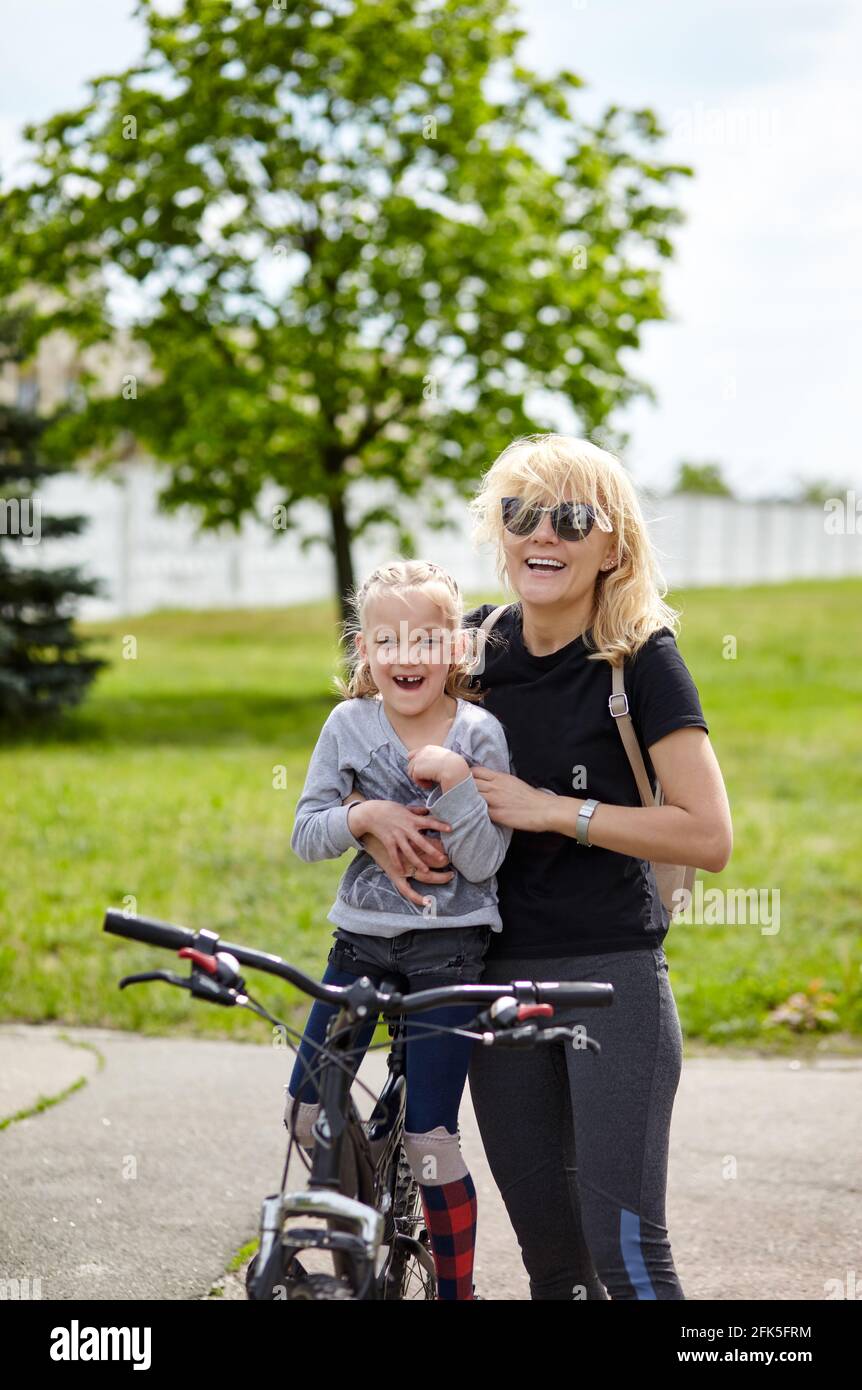 Mom and daughter have fun on the same bike and resting in nature ...