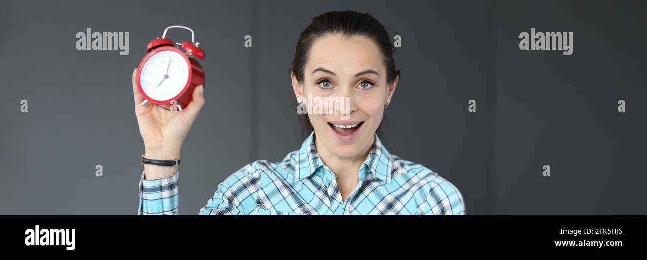 Surprised woman holds red alarm clock in her hand Stock Photo - Alamy