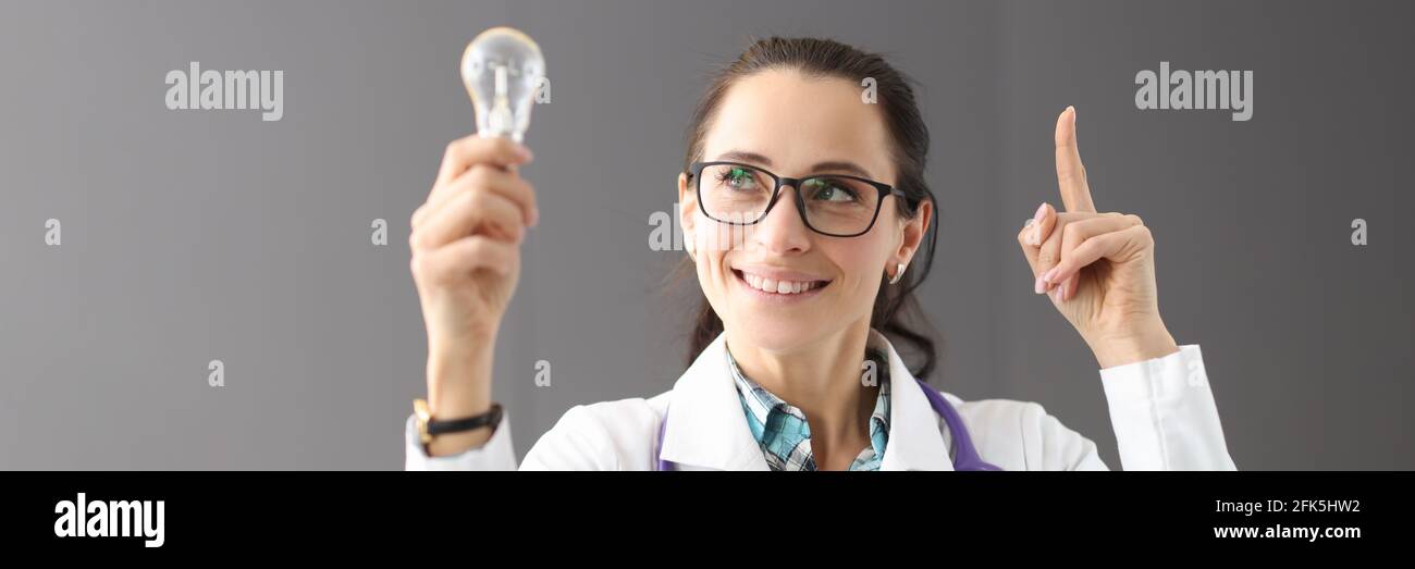 Smiling female doctor holding light bulb and thumb up Stock Photo - Alamy