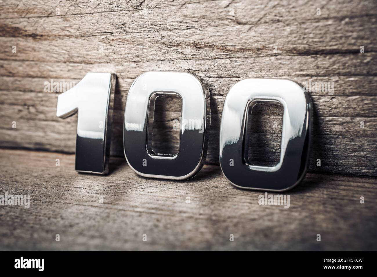 Chrome Number 100 Leaning On A Wooden Wall Stock Photo - Alamy