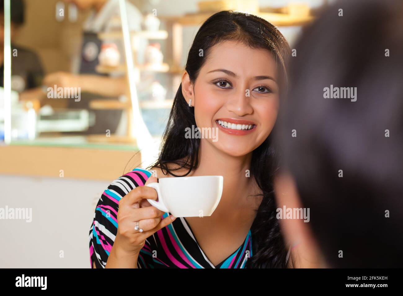 Asian female friends enjoying her leisure time in a cafe, drinking ...