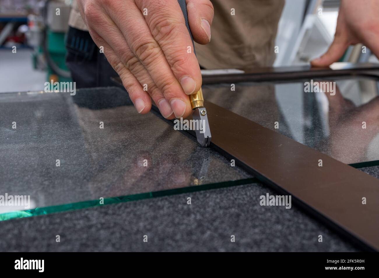 The glazier cuts the glass with a manual cutter. Handicraft plant ...