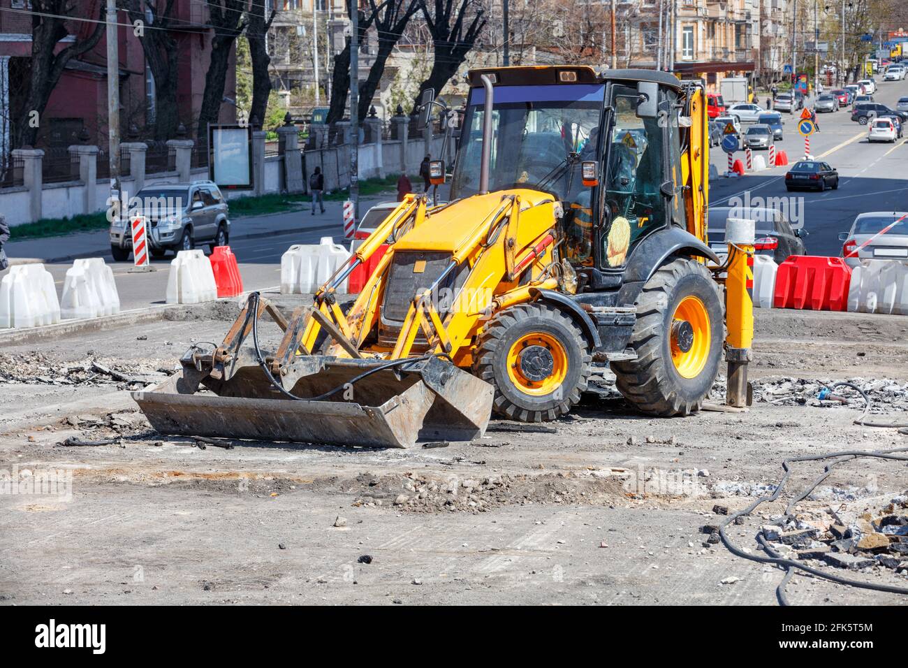 A compact tractor with pavement repair attachments stands on a work ...