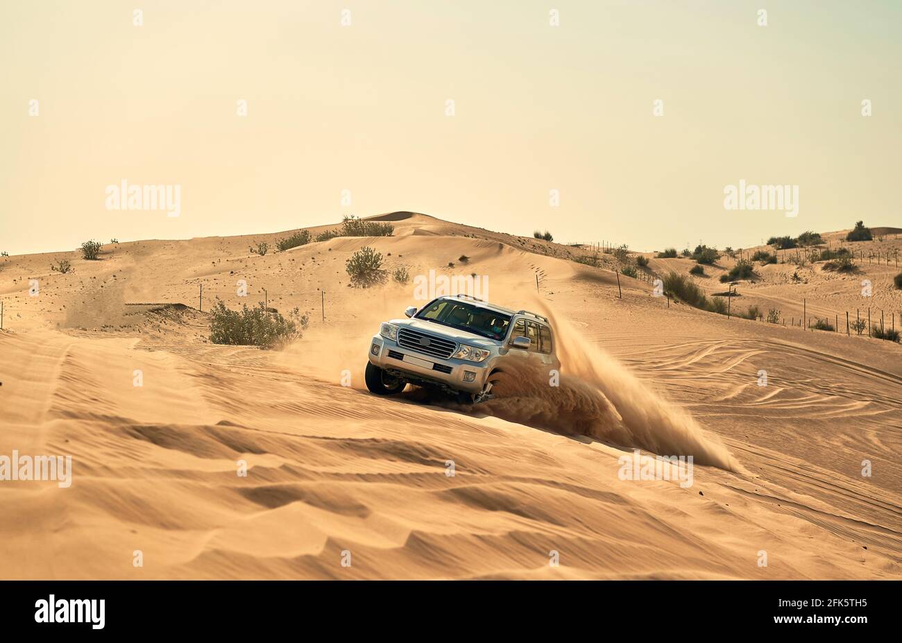 Off-road SUV vehicle speeding through sand dunes in the Arabian desert ...