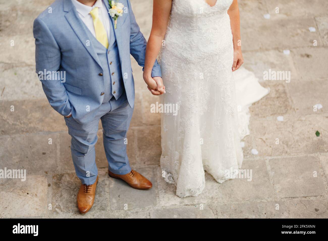 The bride and the groom stand side by side and hold each other's hands ...