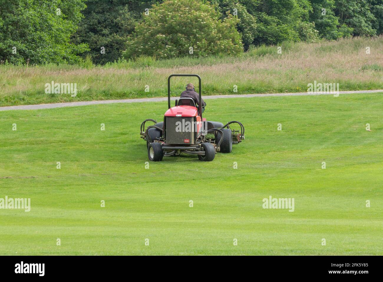 A golf course greenkeeper on a sit on lawn mower Stock Photo - Alamy