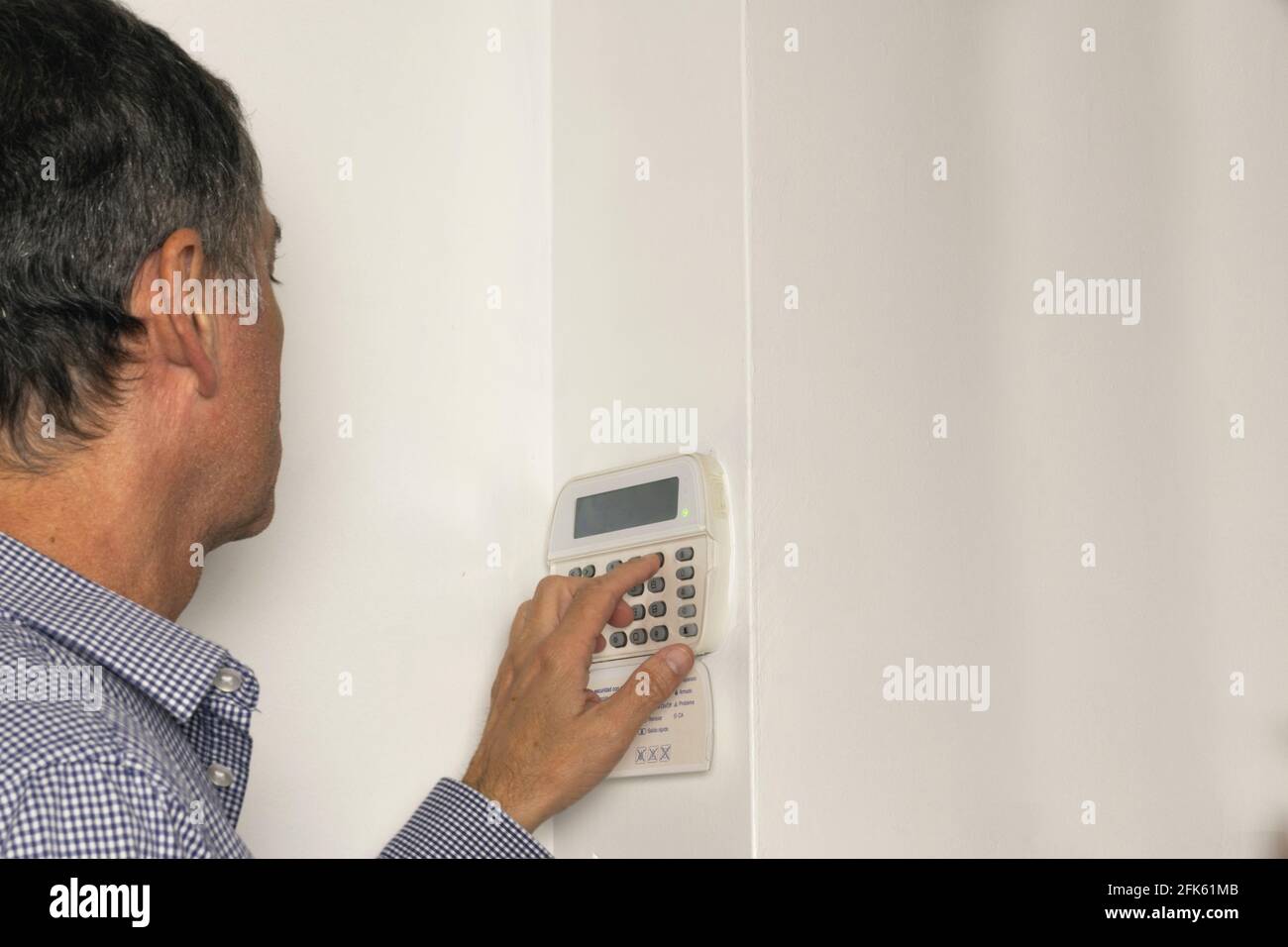 Man operating on an alarm keypad on a white wall Stock Photo - Alamy