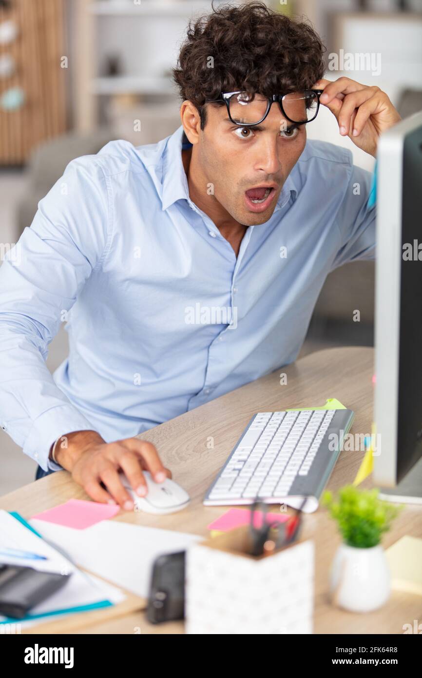 man lifts eyeglasses and stares in shock at computer screen Stock Photo ...